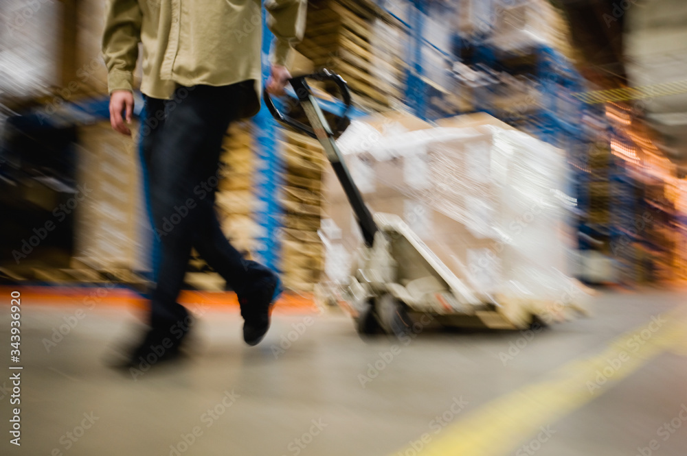 Warehouse worker pulling palette Stock Photo | Adobe Stock