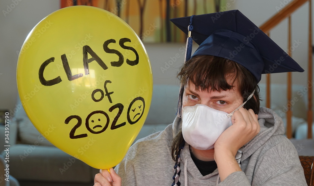 A graduating senior stuck at home in quarantine wears a mask and holds ...