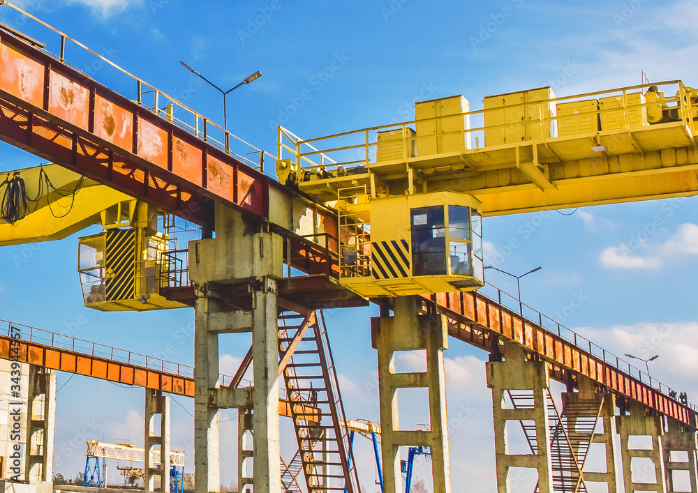 Overhead crane cabin at a construction site on a background of blue sky ...
