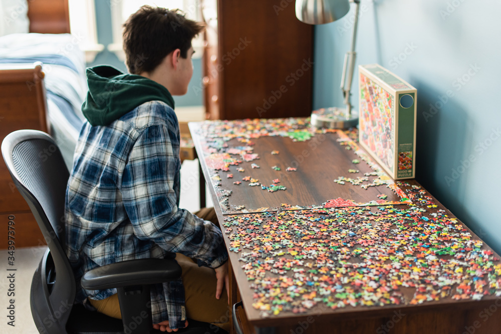 Teen boy working on a jigsaw puzzle in his bedroom during Covid 19 ...