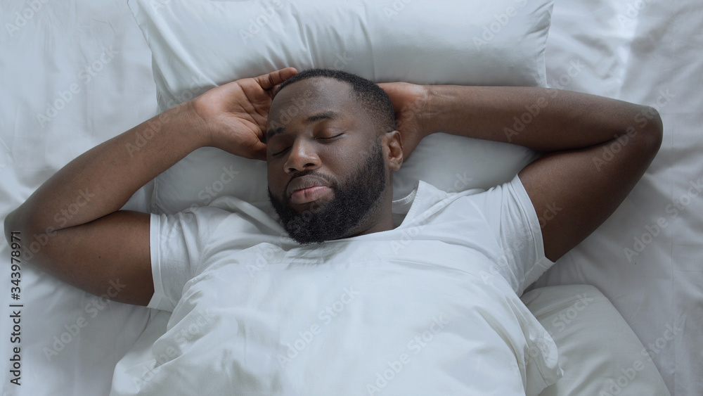 Handsome african american man sleeping in cozy bed seeing sweet dreams ...