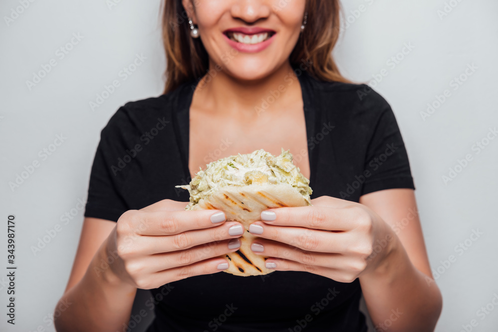 Latin girl holds an arepa in her hands ready to eat it, the arepa is a ...