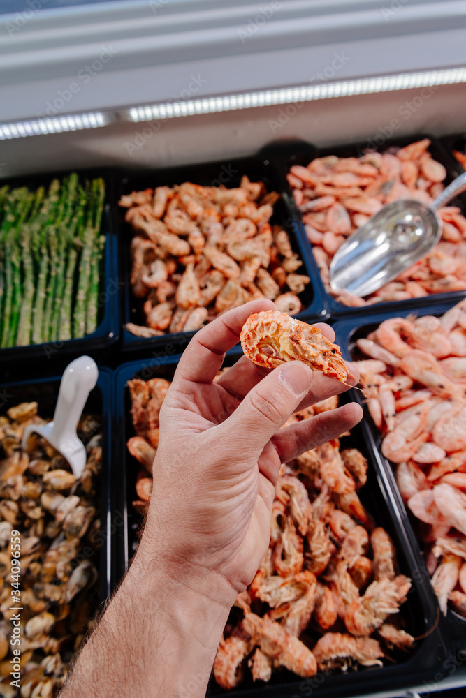 Man holds shrimp in hand in supermarket. Frozen prawns in a supermarket ...