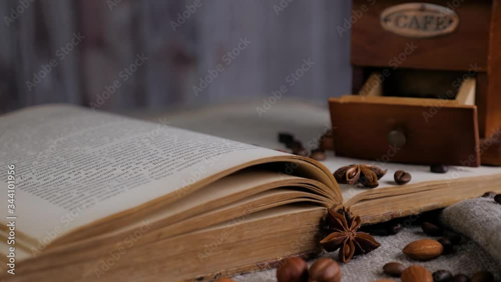 Retro coffee grinder, old book and scattered grains of coffee on ...