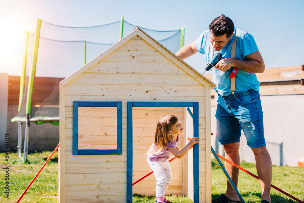 Dad building assembling wooden playhouse with daughter at home in the ...
