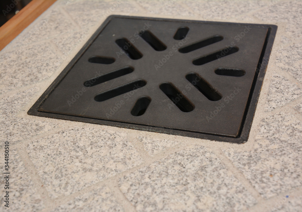 A close-up on yard drainage with metal sump pump cover in a paver ...