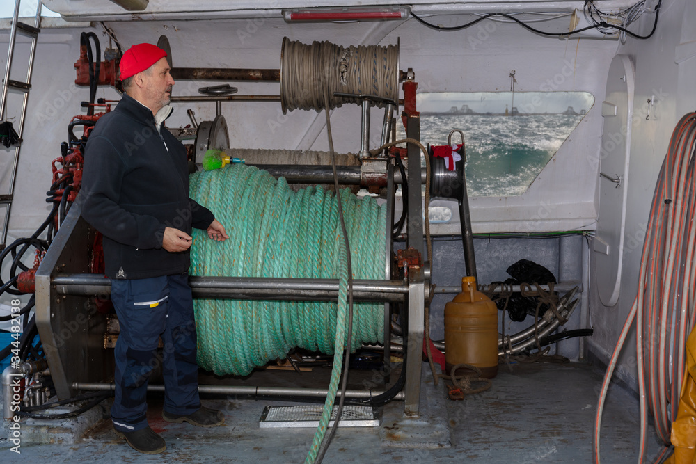 The captain of a fish trawler on his ship at sea during a fishing trip ...
