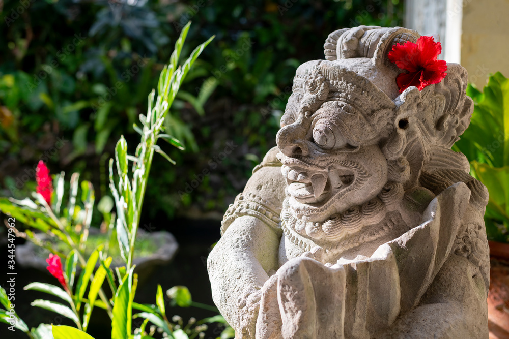 Balinese stone statue of white stone with red hibiscus flower on its ...