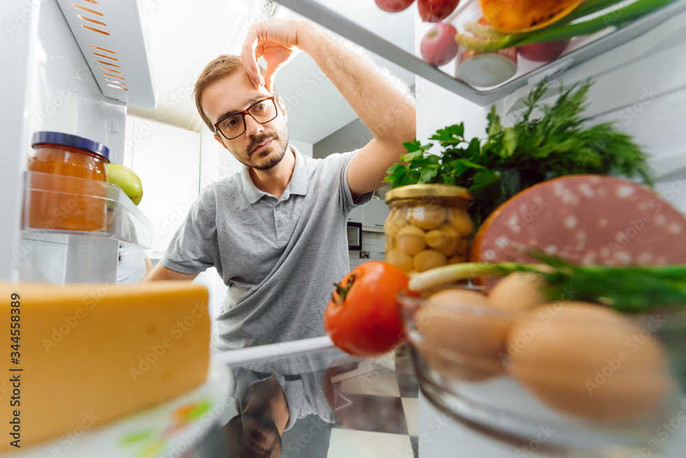 Man looking for something to eat at night while standing in front of ...