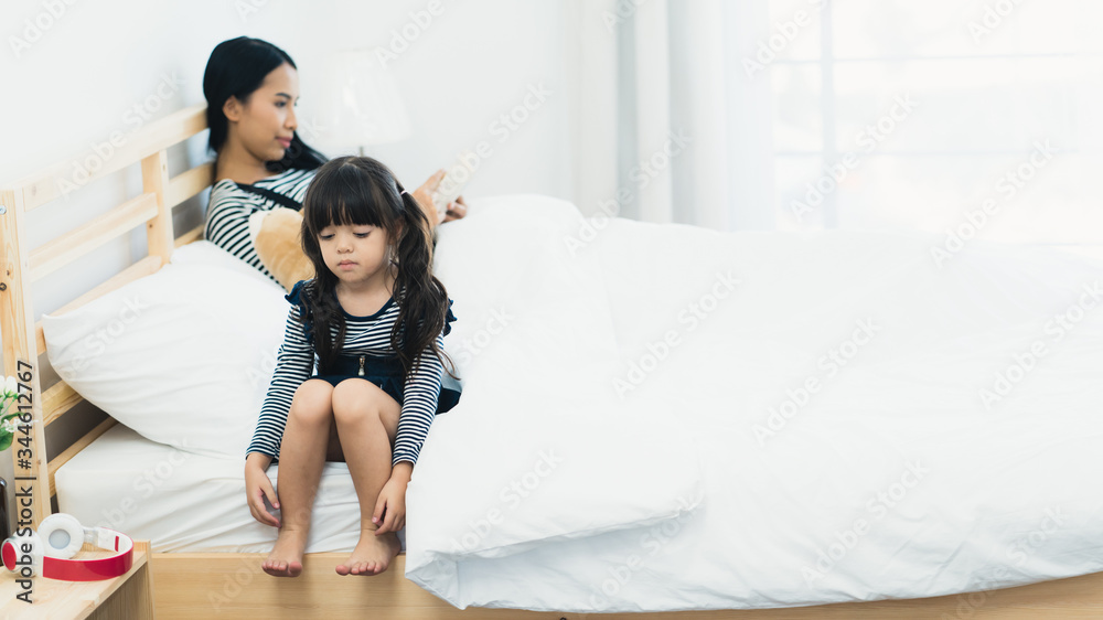 Sad unhappy young daughter upset while mother ignores and keeps playing mobile phone, mother ...