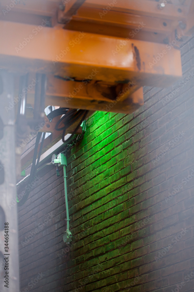 Yellow hoist and green LED light on a brown brick wall. Yellow painted ...