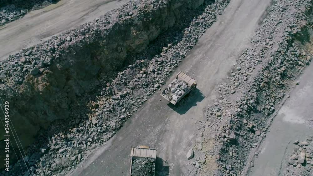 Mining dump trucks in large granite open pit mine. Loaded truck rides ...