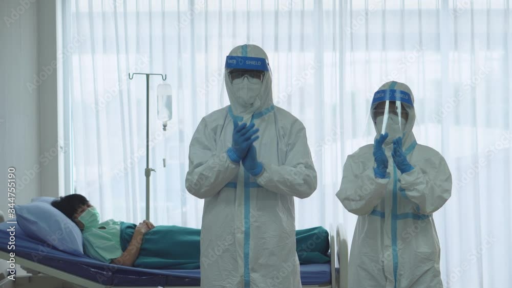 Asian doctor and nurse in personal protective equipment or ppe clapping ...