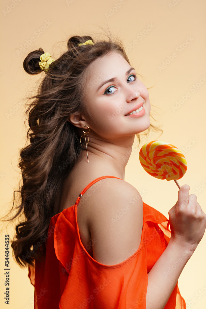 portrait of cute beautiful girl with a round caramel on a colored ...
