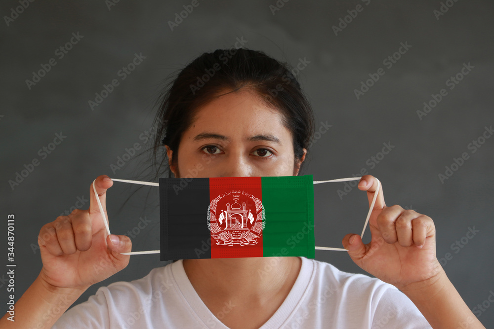 A woman in white shirt with Afghanistan flag on hygienic mask in her ...
