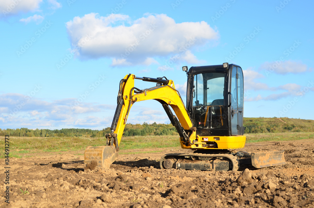 Mini excavator digging earth in a field or forest. Laying underground ...