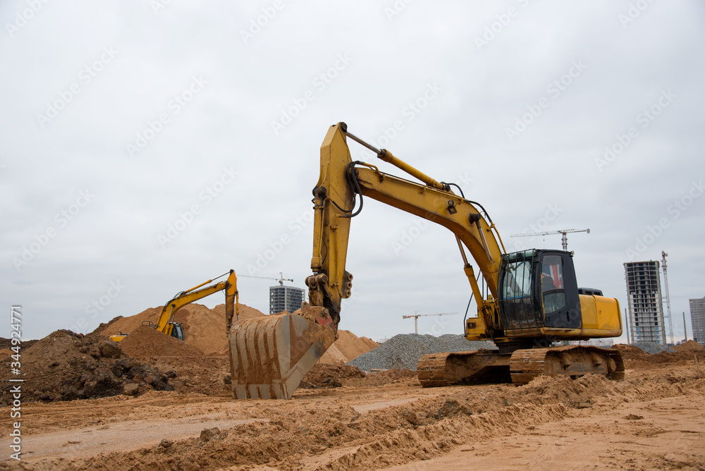 Excavator at earthworks on construction site. Backhoe loader digs a pit ...