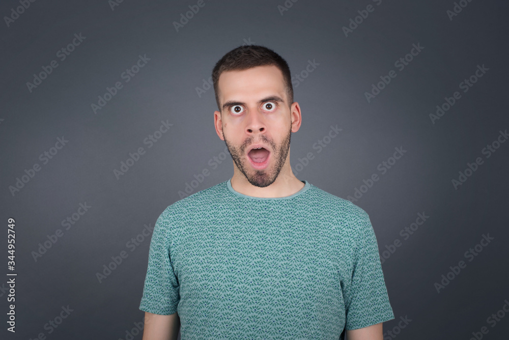 Emotional attractive male with opened mouth expresses great surprisment ...