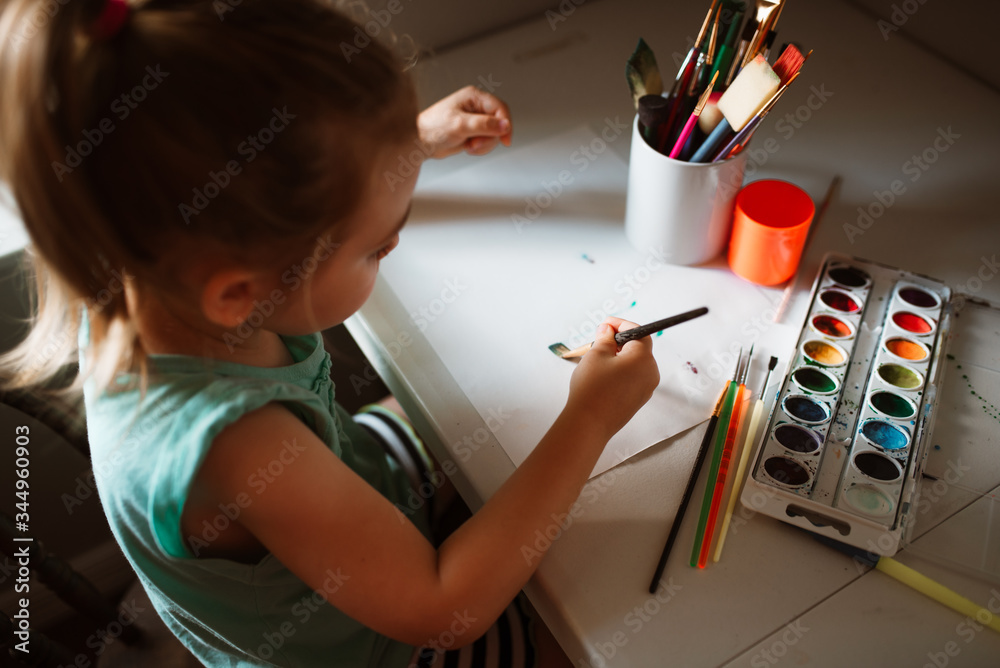 Child painting by the window with paint. Creative little artist at work ...