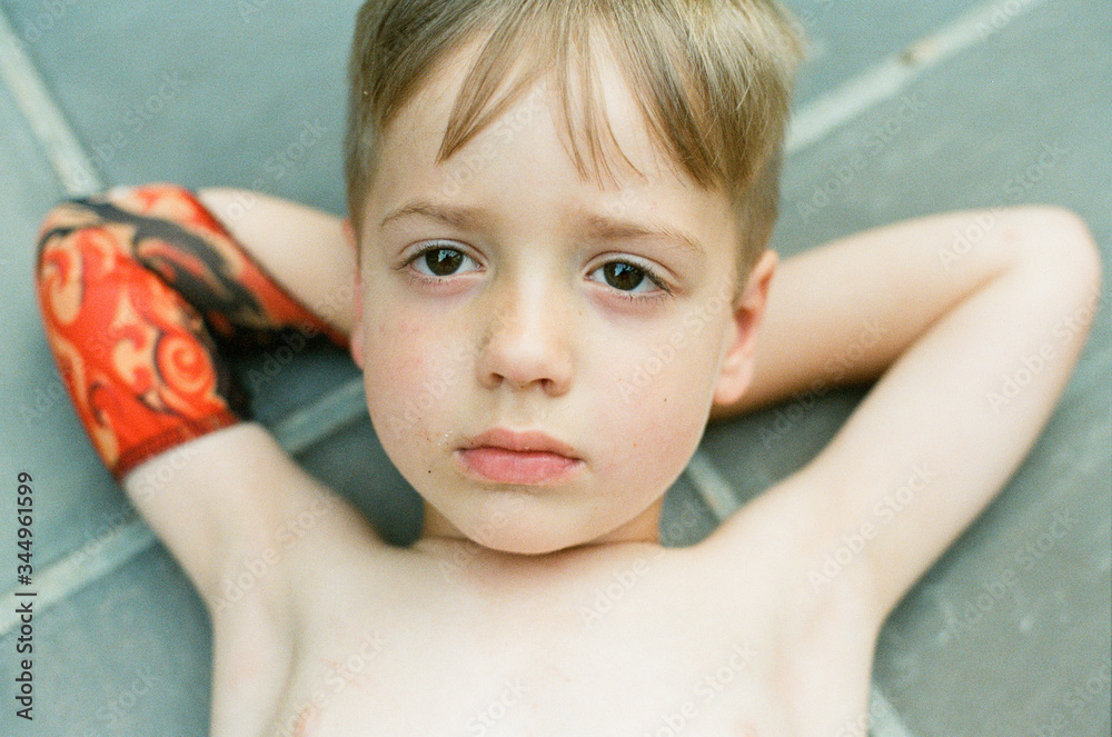 Cute young boy lying on a floor looking serious Stock Photo | Adobe Stock
