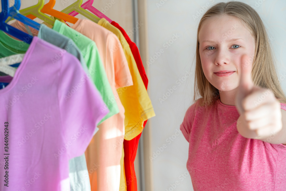 Young girl choosing outfit from wardrobe closet with different colors ...
