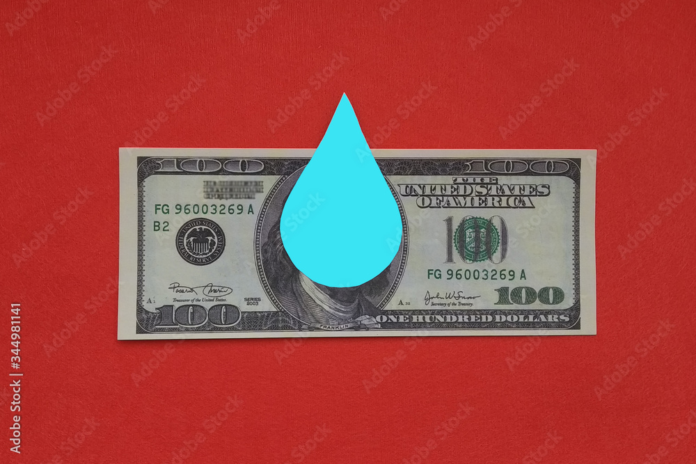American dollar bill, a drop of water on a red background. Cost of ...