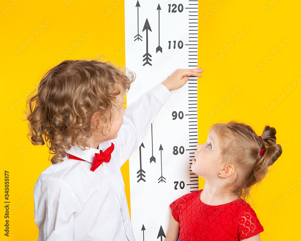 The older brother measures the height of the younger sister using a ...