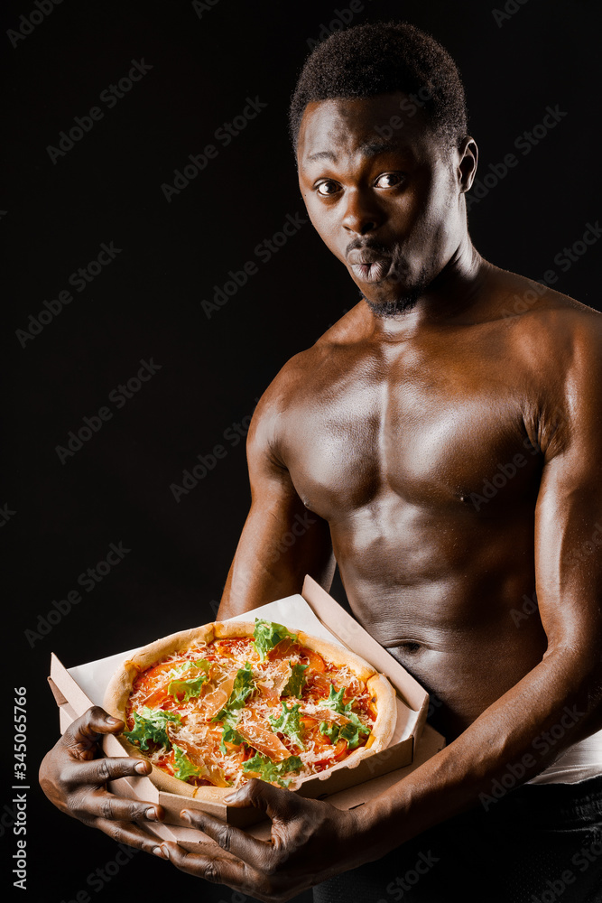 Surprised black fit man with pizza in hands. Tasty food delivery ...