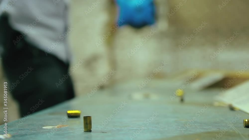 Cinemagraph of empty pistol bullet shell dropping and impacting wooden ...