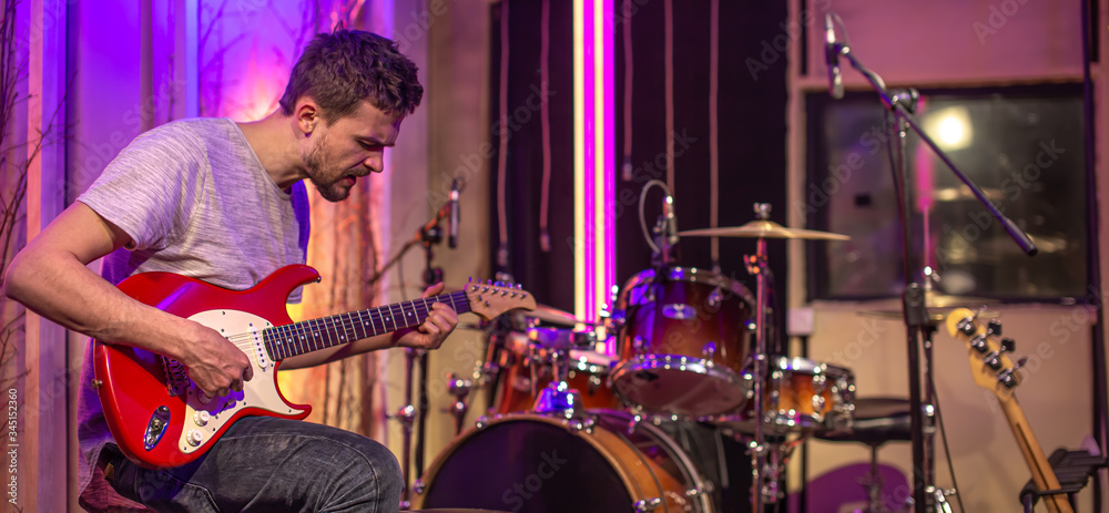A man plays an electric guitar in a recording Studio. A rehearsal room ...