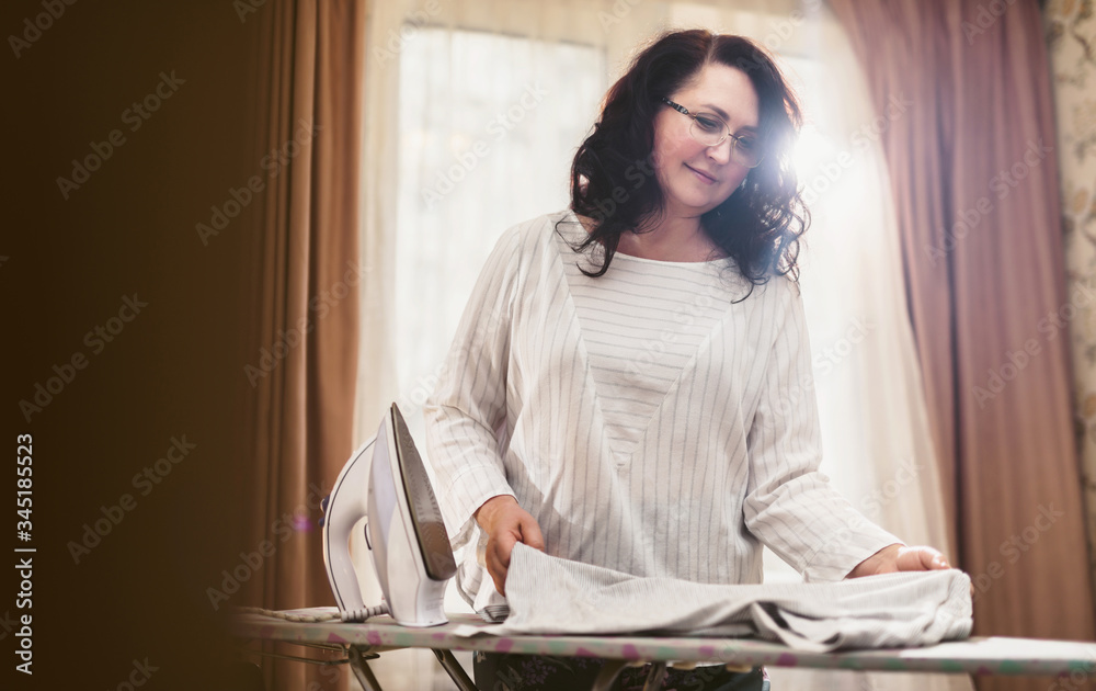 Foto de Pleasant senior woman ironing clothes using steam. Steaming ...
