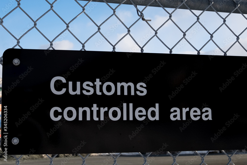 Poster A black metal display sign with customs controlled area written ...