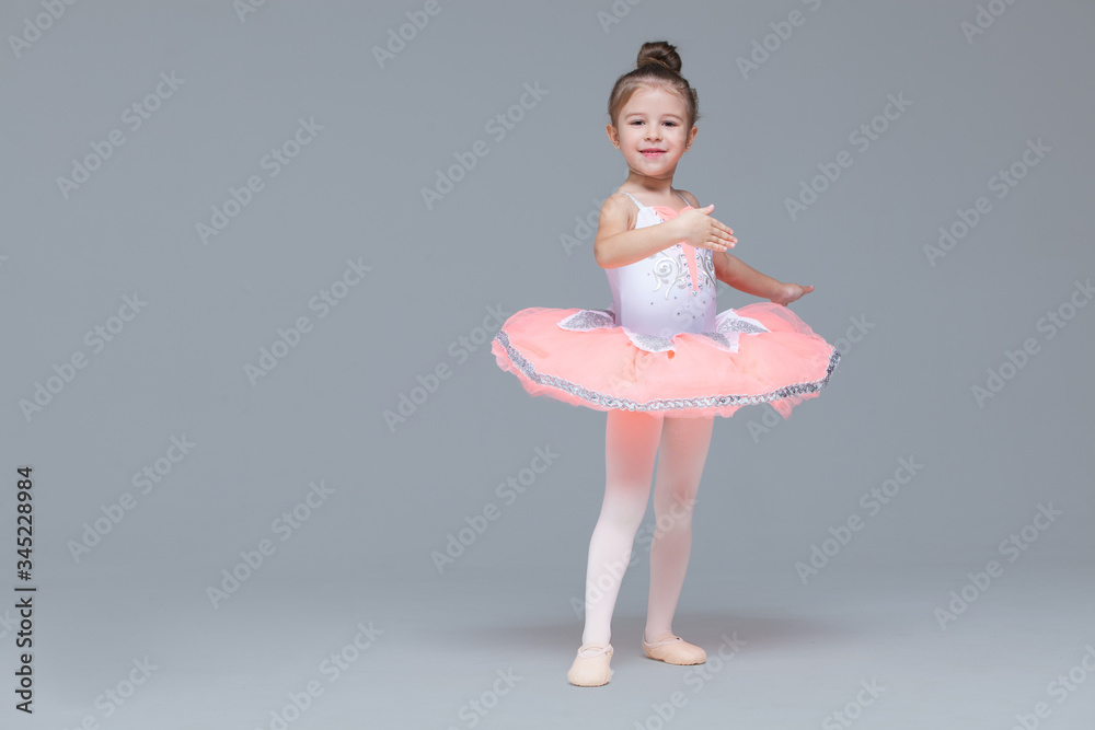 Cute adorable ballerina little girl in pink tutu dance practices ballet ...