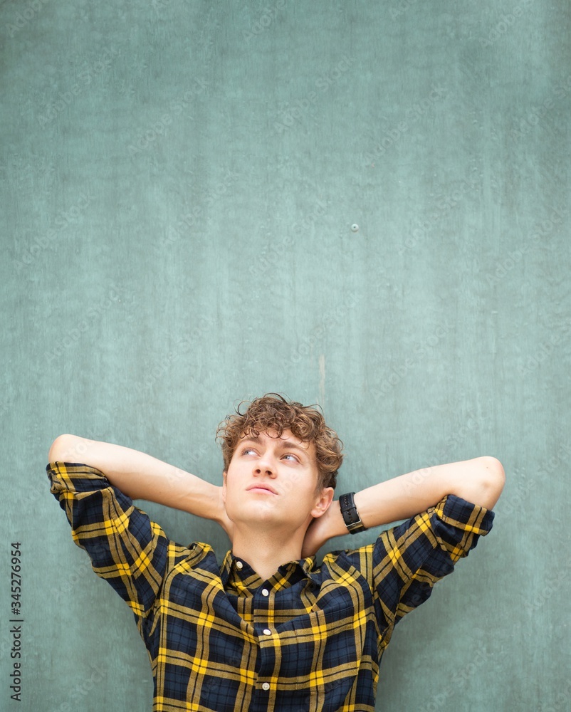 thinking man leaning against green wall with hands behind head Stock ...