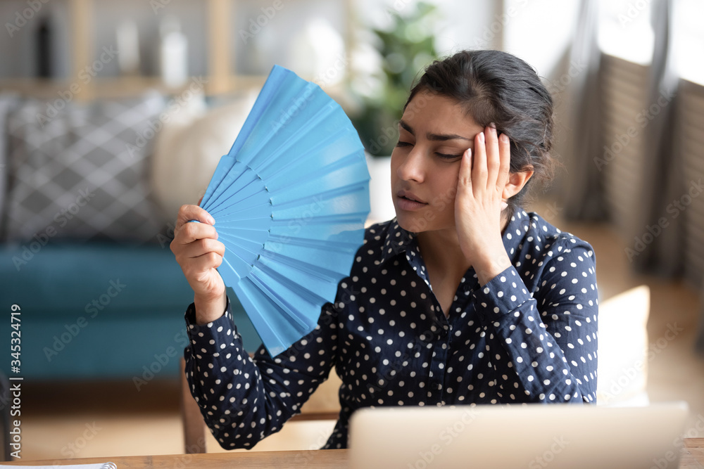 Head shot young exhausted indian woman waving paper fan, suffering from ...
