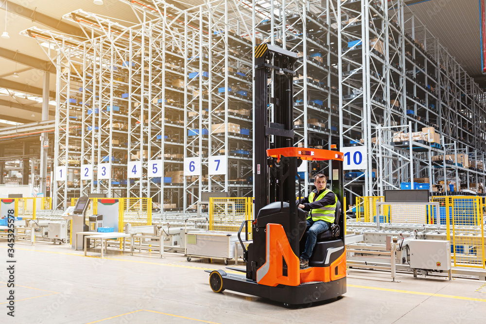 Storehouse employee in uniform working on reachtruck in modern ...