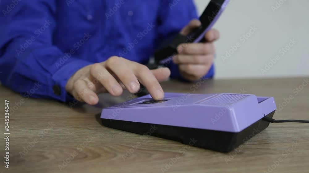Landline phone. A man in a blue overalls is talking on a stationary ...