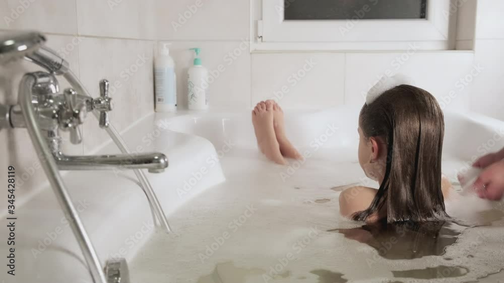 Close-up of a pretty little girl squishes feet in a bathtub full of ...