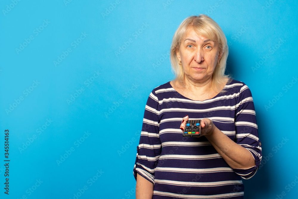 Portrait of an old friendly woman in a striped T-shirt with a remote ...