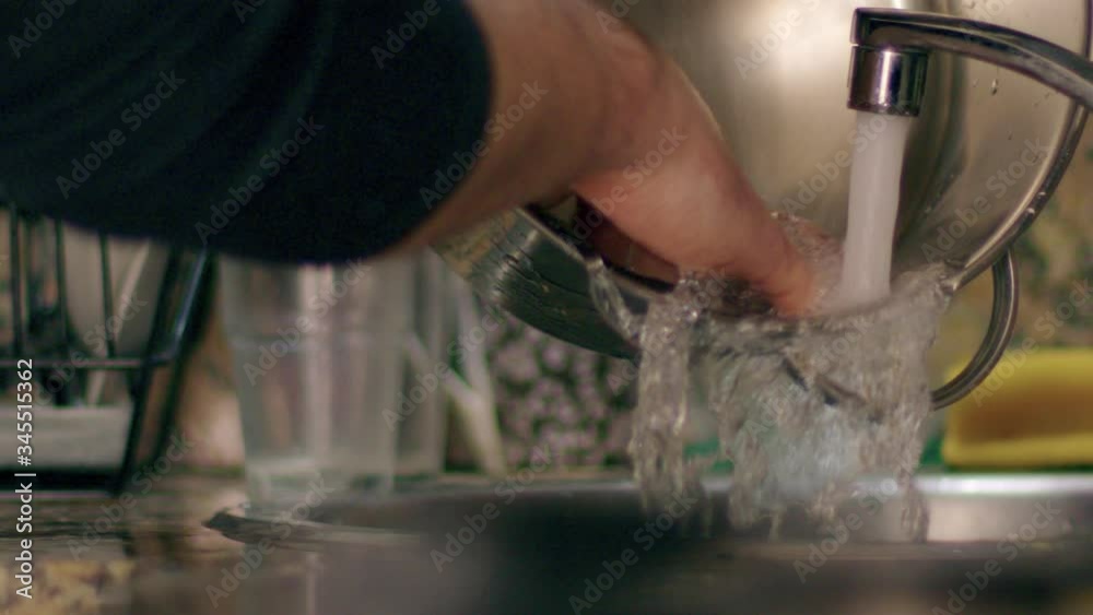 Close up of a Man cleaning a pan pot and pouring water during house ...