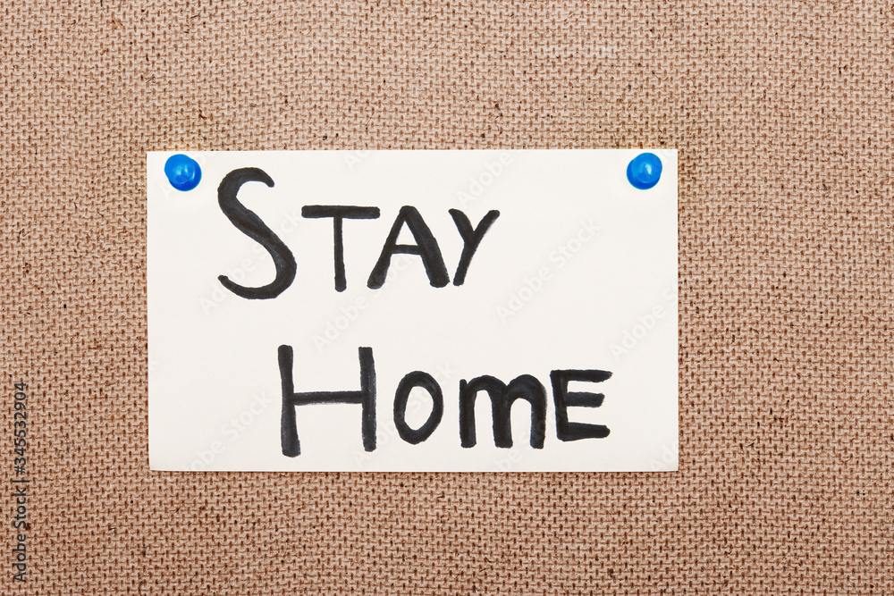 Adhesive note with Stay Home text attached to the bulletin board by ...