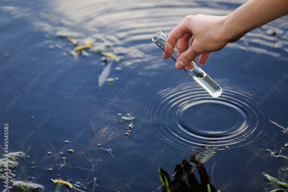 a specialist s hand draws water into a flask from a river for further ...