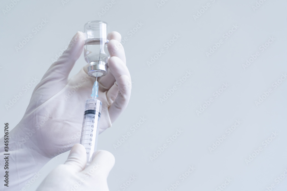 Medical staff in PPE suit holding syringes and vaccines for the ...