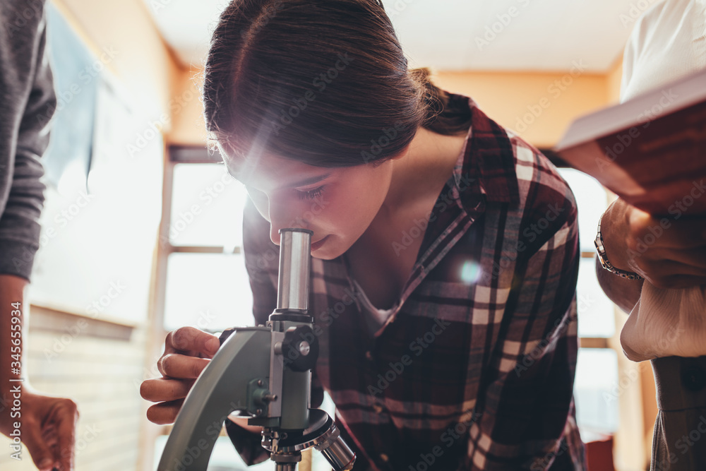 Student looking through microscope in biology class Stock Photo | Adobe ...