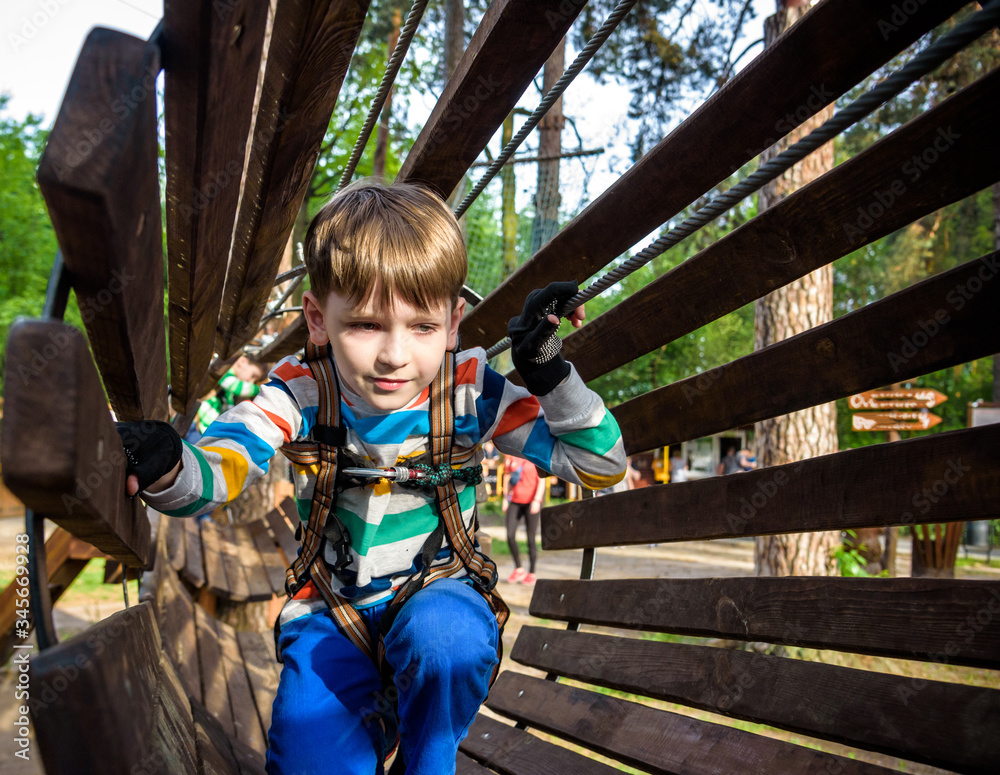 Happy kid overcomes obstacles in rope adventure park. Summer holidays ...