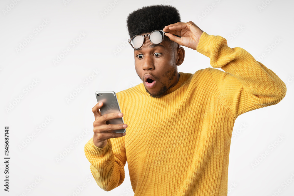 Shocked african man while watching in smartphone on isolated white ...