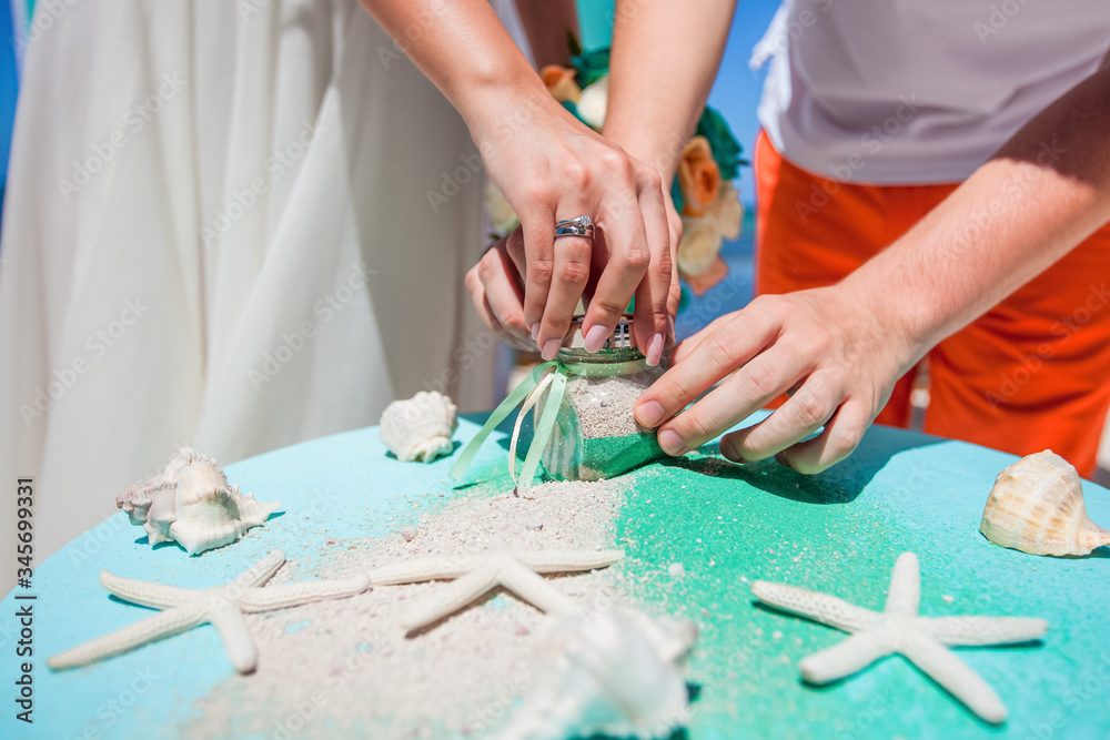 Bride and groom pouring colorful different colored sands into the ...