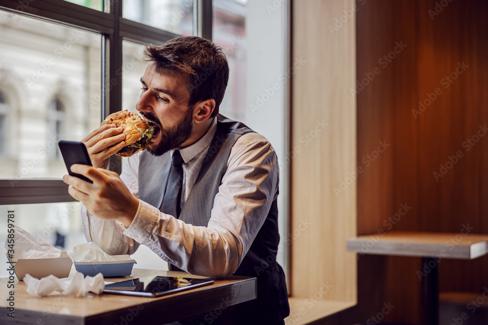 Hungry businessman sitting on lunch break in fast food restaurant ...