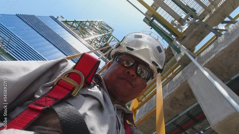 A worker wearing a safety belt climb on a ladder for working at height ...