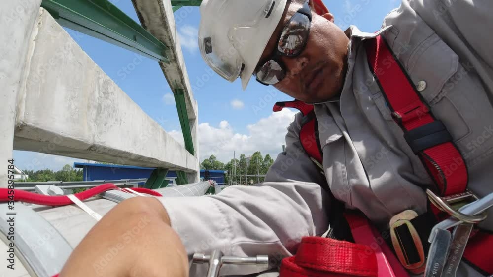 A worker wearing a safety belt climb on a ladder for working at height ...
